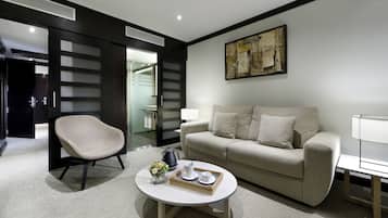 Uma sala de estar moderna com um sofá, poltrona, mesa de centro e um quadro na parede.