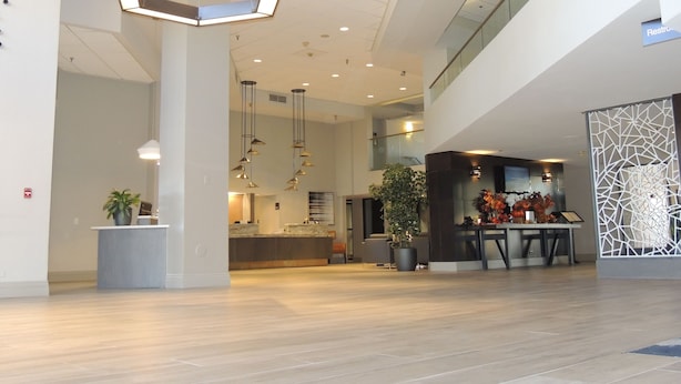 Um hall amplo com design moderno, com área de estar central, balcão de recepção e parede decorativa.