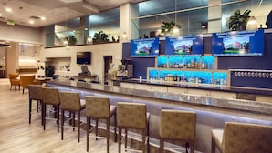 Um saguão de hotel com área de bar, assentos e balcão de recepção.