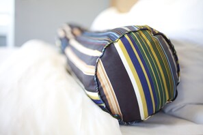 Cama com almofadas listradas e roupa de cama branca.