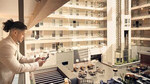 Um lobby de hotel moderno com vários andares, um átrio central e diversas áreas de estar.