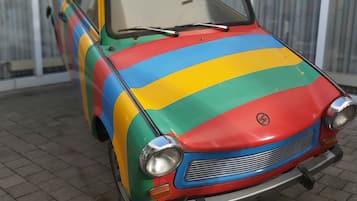 Um carro antigo e colorido estacionado em frente a um edifício com grandes janelas.