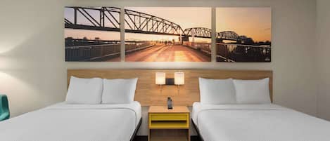 Quarto de hotel com duas camas, cabeceira de madeira, abajures e uma grande obra de arte na parede retratando uma ponte.