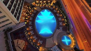 Piscina circular com espreguiçadeiras ao redor e uma fonte no centro.