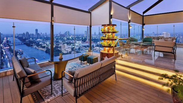 Apartamento alto com vista panorâmica da cidade, arranjo de plantas central e móveis modernos.