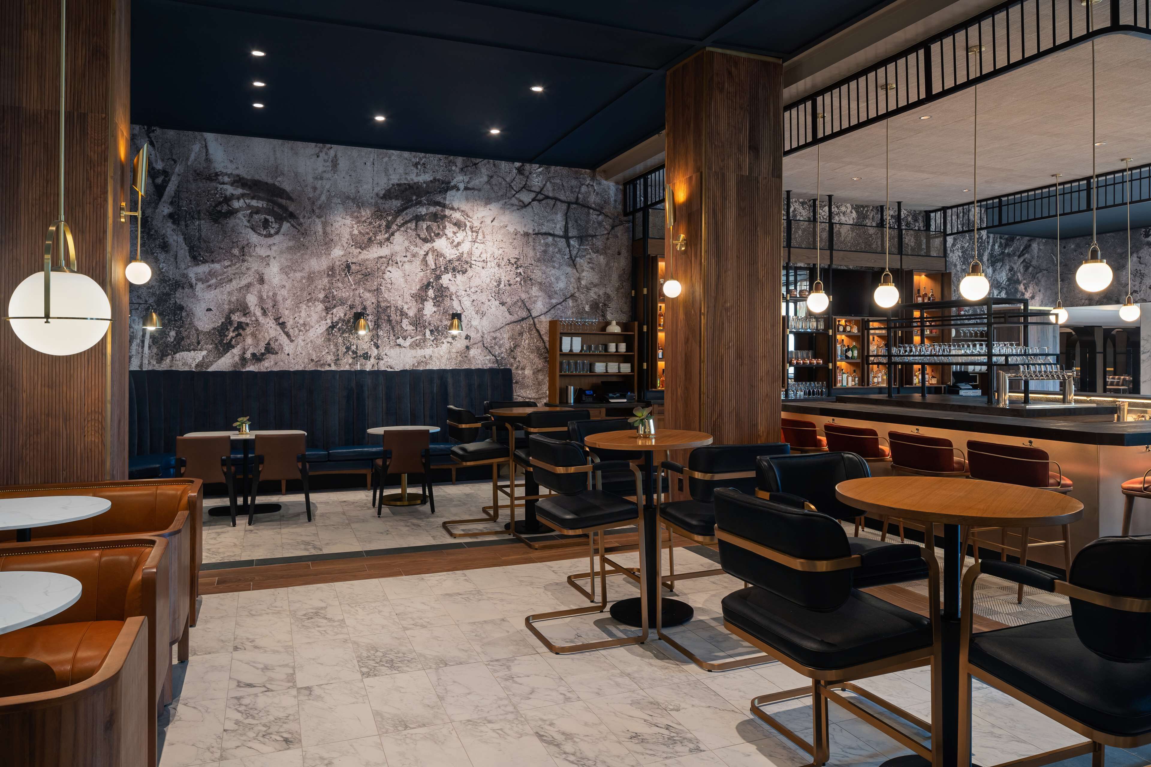 Uma área de bar moderna com assentos e um grande mural na parede.
