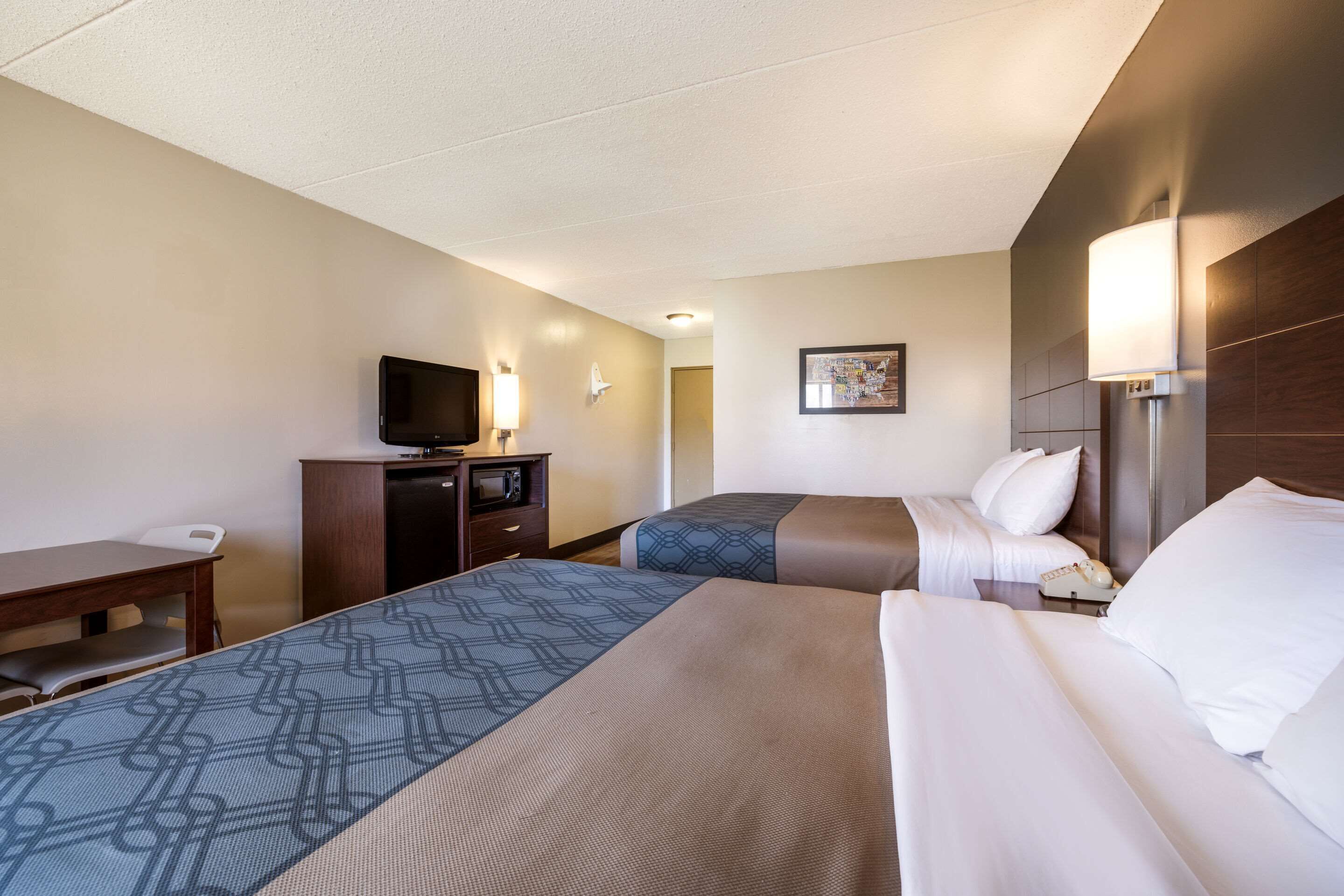 Quarto de hotel com duas camas, uma mesa, televisão e uma pequena cozinha.