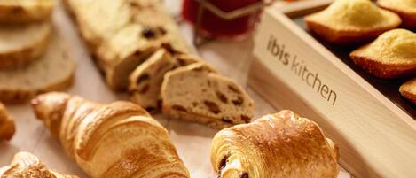 Diversos produtos de panificação, incluindo croissants e pão, com uma etiqueta que diz 'Ibis Kitchen'.