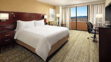 Quarto de hotel com uma cama grande, uma escrivaninha, uma cadeira e vista para a cidade.