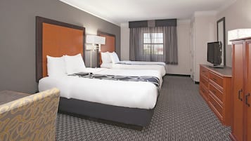 Quarto de hotel com duas camas, televisão, cómoda e janela com cortinas.