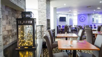 Um restaurante com paredes de tijolo, lareira e mesas com cadeiras.