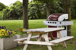 Uma mesa de piquenique com churrasqueira em um parque.