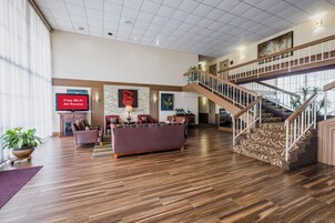 Um hall de hotel espaçoso com um sofá grande, uma lareira, uma escada e uma placa indicando Wi-Fi gratuito.
