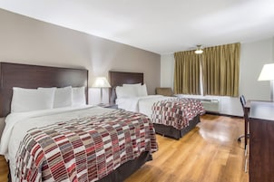 Quarto de hotel com duas camas, uma mesa e uma cadeira.