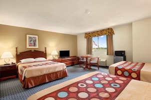 Quarto de hotel com duas camas, uma escrivaninha, televisão e uma janela com a bandeira americana.