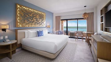 Quarto de hotel com uma cama grande, uma escrivaninha, uma cadeira e vista para o mar.