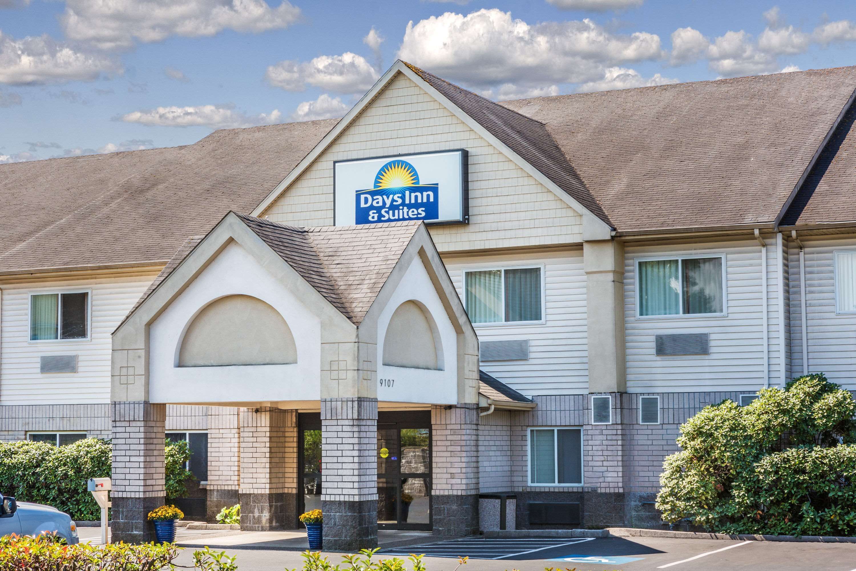 Edifício Days Inn & Suites com fachada de tijolos, ampla entrada em arco e estacionamento.