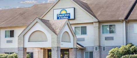 Edifício Days Inn & Suites com fachada de tijolos, ampla entrada em arco e estacionamento.