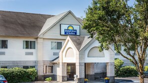 Edifício do Days Inn & Suites com uma placa chamativa, estacionamento e uma árvore na frente.