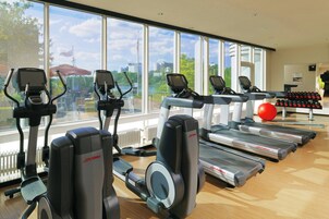 Uma academia com esteiras, elípticos e uma bola de exercício vermelha.