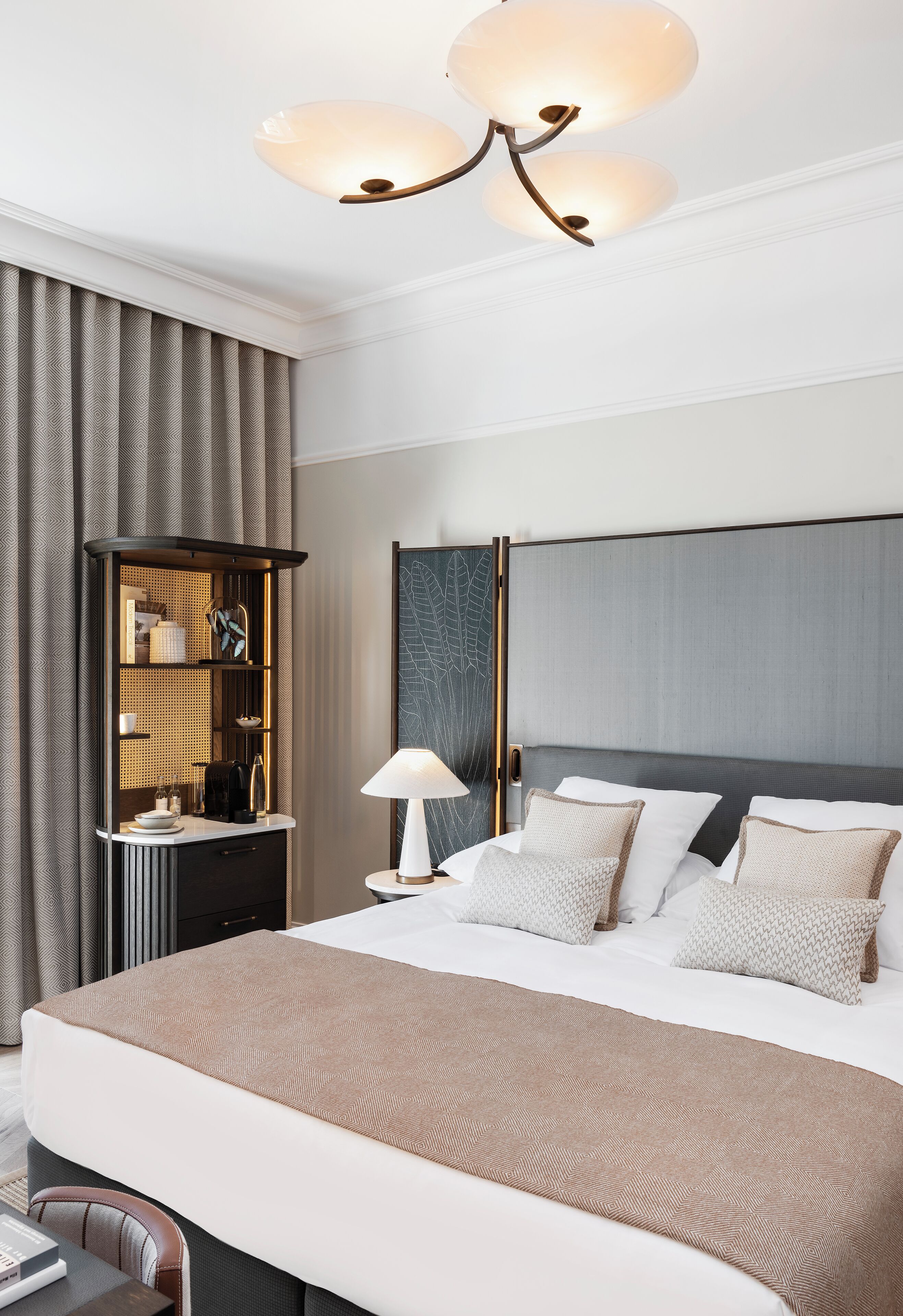 Quarto de hotel moderno com cama grande, mesa de cabeceira, luminária e armário embutido.