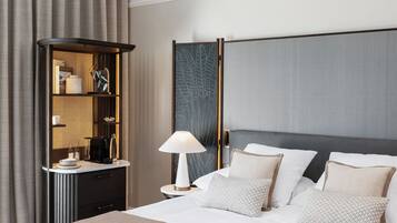 Quarto de hotel moderno com cama grande, mesa de cabeceira, luminária e armário embutido.
