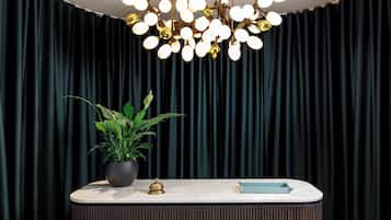 Balcão de recepção com design moderno, um vaso de planta e um lustre único.
