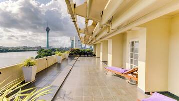 Terraço no telhado com vista para uma torre, plantas em vasos e cadeiras de descanso.