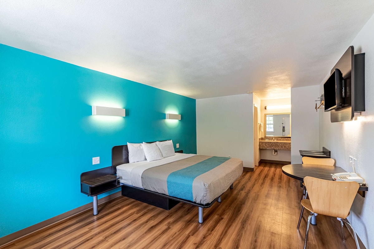 Quarto de hotel moderno com cama, escrivaninha e uma cadeira.