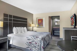 Quarto de hotel com cama, mesa de cabeceira, luminária, obras de arte e televisão.