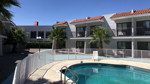 Um hotel com piscina, paredes brancas e telhados de telha vermelha.