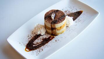 Sobremesa em um prato branco com chantilly e calda de chocolate.