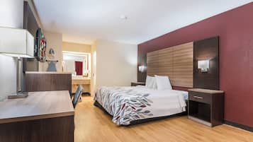Quarto de hotel com cama, mesa de cabeceira, luminária e vista para o banheiro.