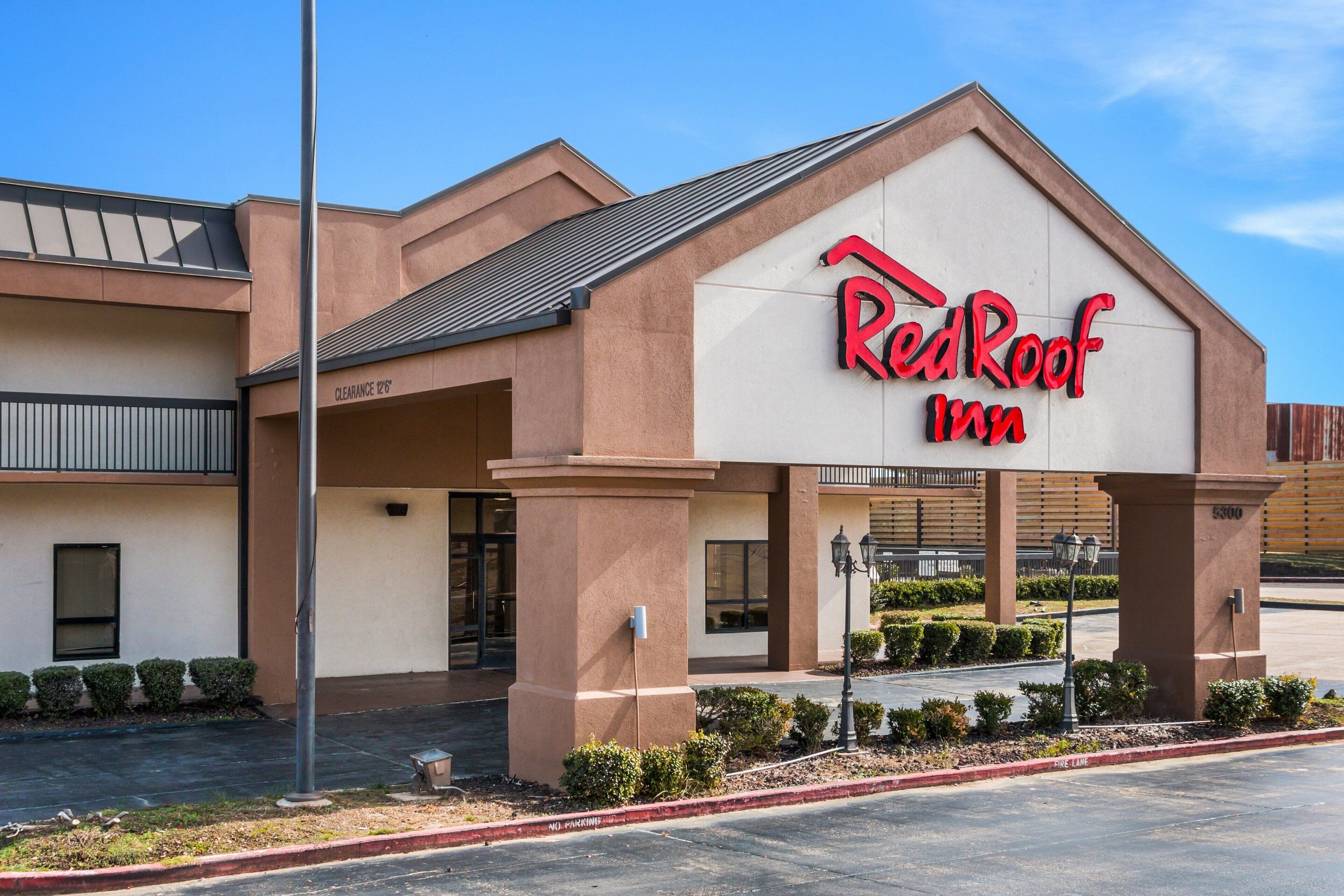 Edifício Red Roof Inn com placa visível, faixa de incêndio e estacionamento.