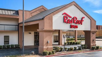 Edifício Red Roof Inn com placa visível, faixa de incêndio e estacionamento.
