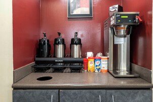 Uma cozinha compacta com cafeteira, dois termos e três frascos de leite condensado.