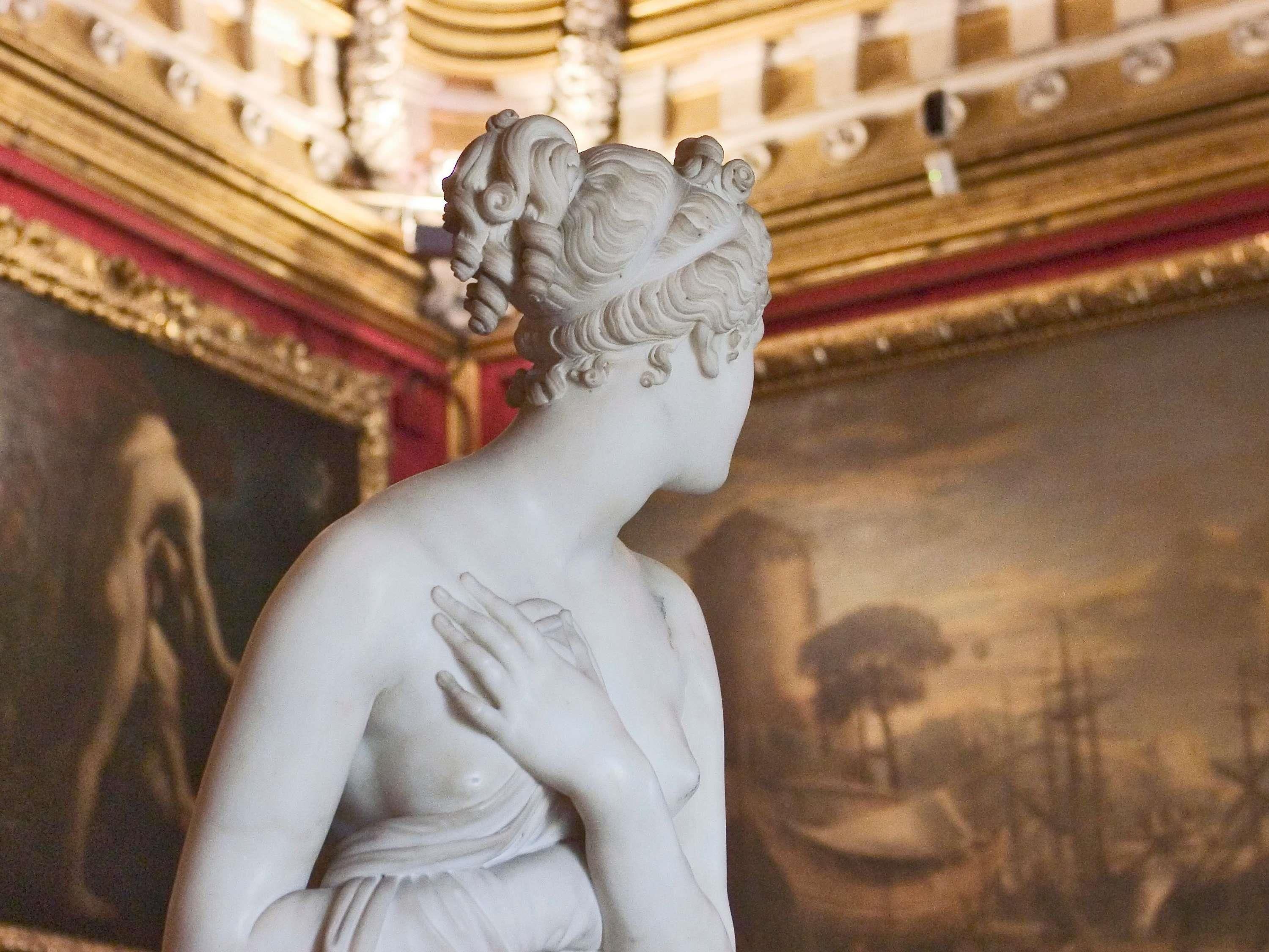 Uma estátua de mármore com detalhes complexos no cabelo e pose clássica.