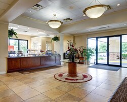 Um hall amplo com balcão de recepção, área de café e uma grande janela com vista para o exterior.