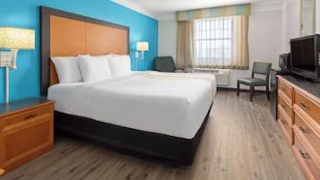 Quarto de hotel com uma cama grande, televisão, escrivaninha e uma cadeira.