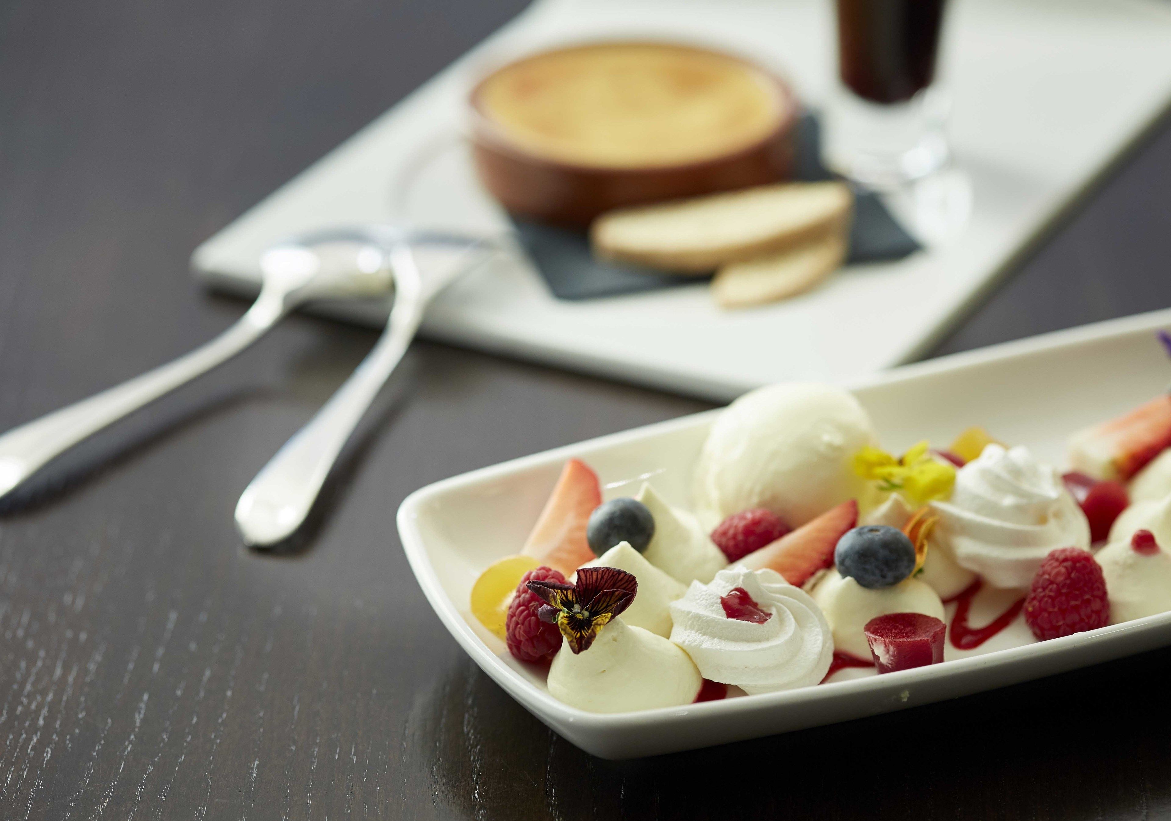Prato de sobremesa com sorvete, frutas e chantilly.