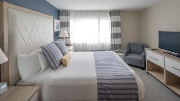 Quarto de hotel com uma cama grande, televisão, escrivaninha e uma cadeira.