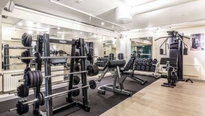Uma academia com equipamentos de musculação, espelhos e halteres.