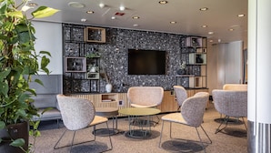 Uma área de estar moderna com assentos, televisão de tela plana e prateleiras decorativas.