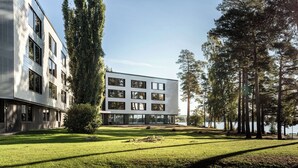 Um edifício moderno com telhado plano, janelas amplas e uma área gramada na frente.