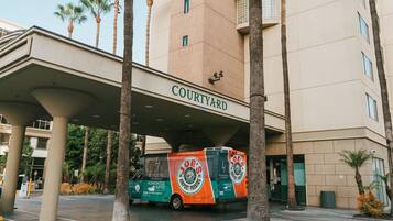 Um edifício com uma placa que diz "COURTYARD" e um ônibus com a marcação "JOE'S AIRPORT PARKING" estacionado na frente.