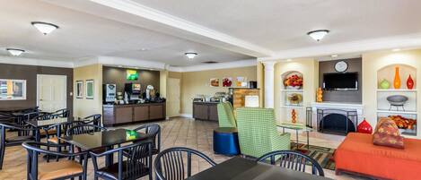 Um saguão de hotel com área de refeições, cozinha e sala de estar com lareira.