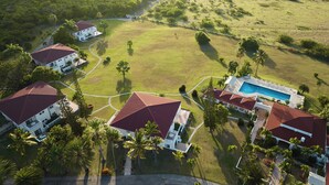 Vista aérea de um resort com vários edifícios, uma piscina e um gramado bem cuidado.