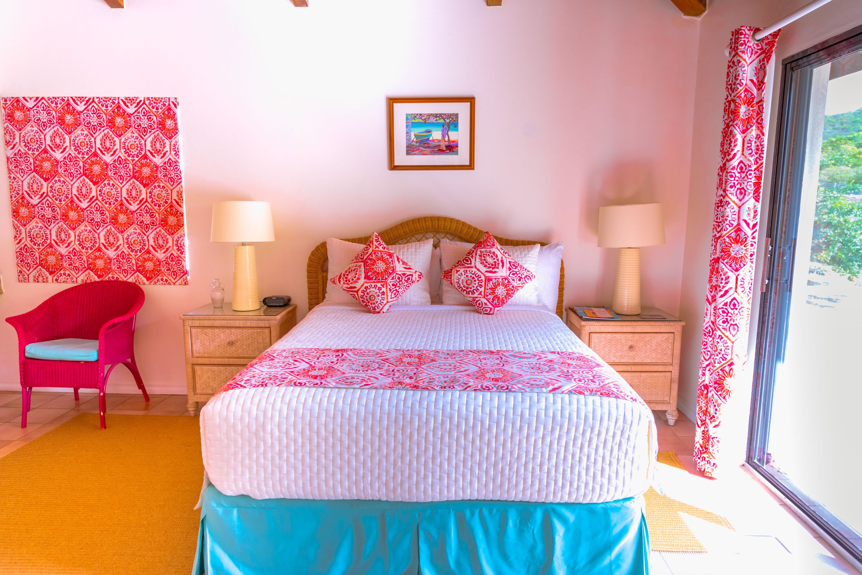 Quarto com cama, duas mesas de cabeceira, um criado-mudo, uma cadeira vermelha, uma janela com cortinas e uma tapeçaria na parede.