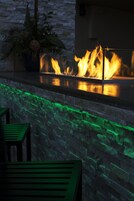 Paredão de pedra com lareira e iluminação verde.