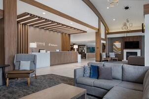 Um lobby de hotel moderno com balcão de recepção, área de estar e lareira.